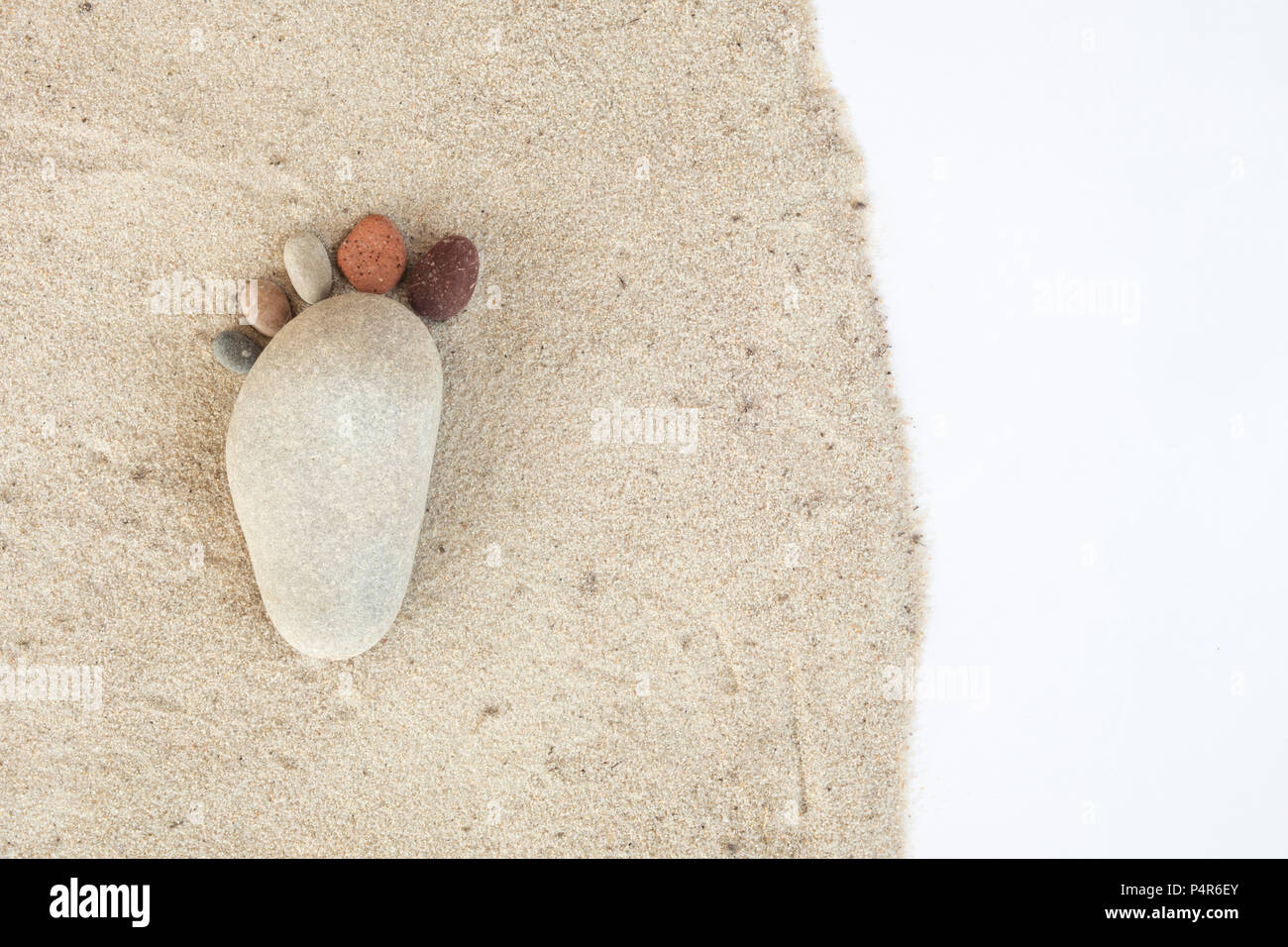 Group of pebble stones on sand creating de form of a foot in isolated ...