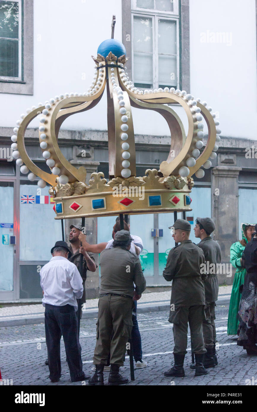 Men of various ages carrying a giant crown in a procession known as ...