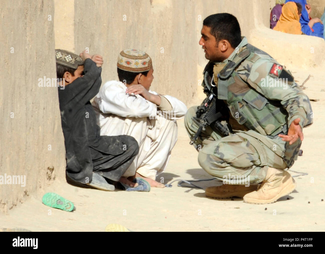 A soldier from the 8th Commando Kandak speaks with children near ...