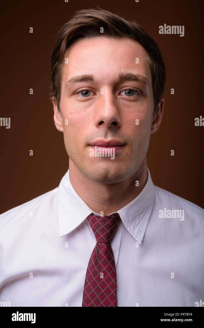 Young handsome businessman against brown background Stock Photo - Alamy