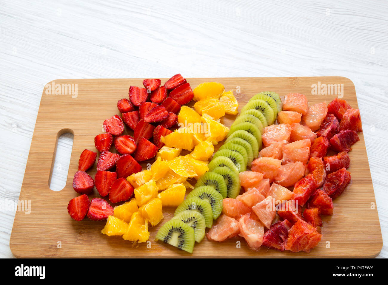 Chopped fresh raw colorful fruits arranged on cutting board on white ...