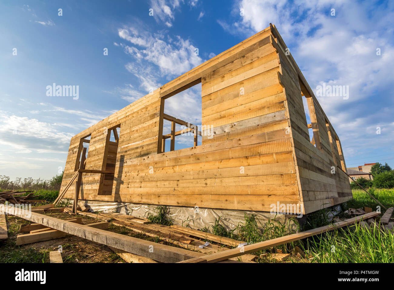 Unfinished ecological house under construction in green field on blue ...