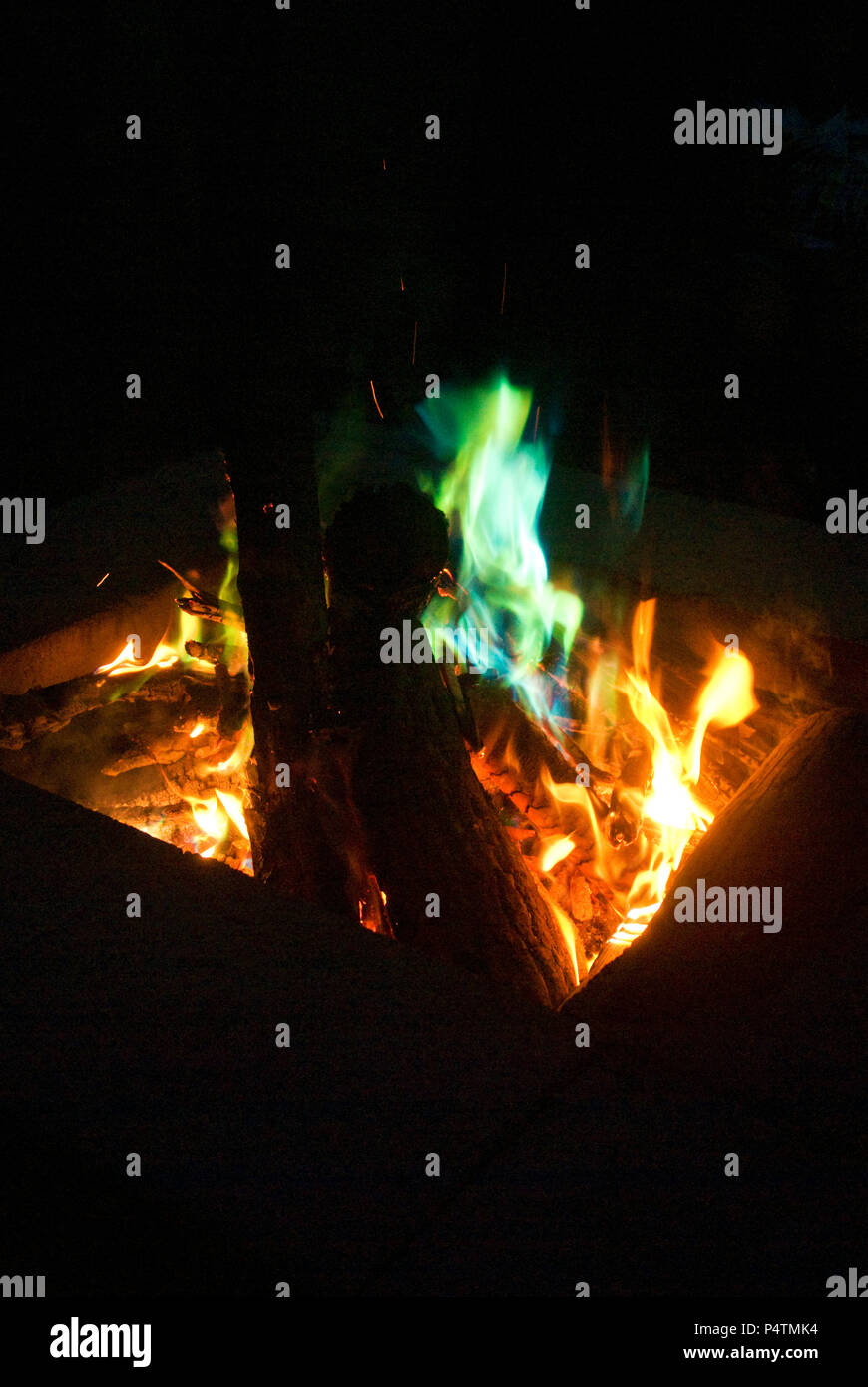 Green Flames wrap around logs inside a campfire Stock Photo - Alamy