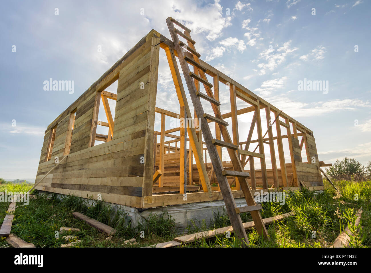Unfinished ecological house under construction in green field on blue ...