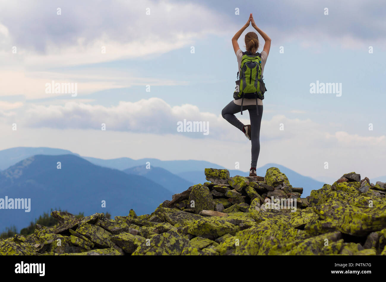 Back view of young slim tourist girl with backpack standing on one leg ...