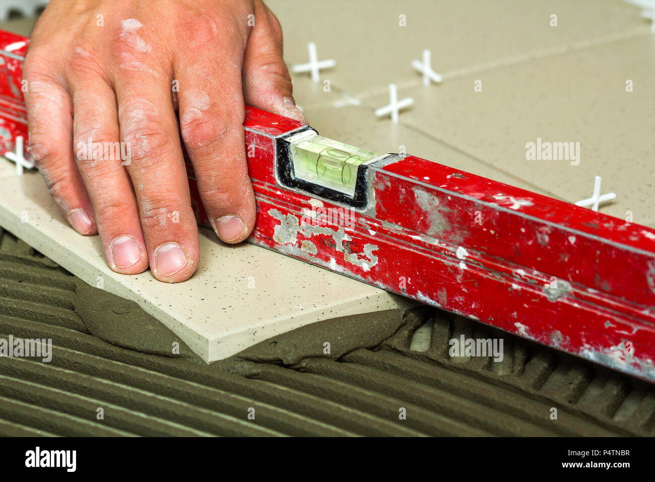 Ceramic tiles and tools for tiler. Worker hand installing floor tiles ...