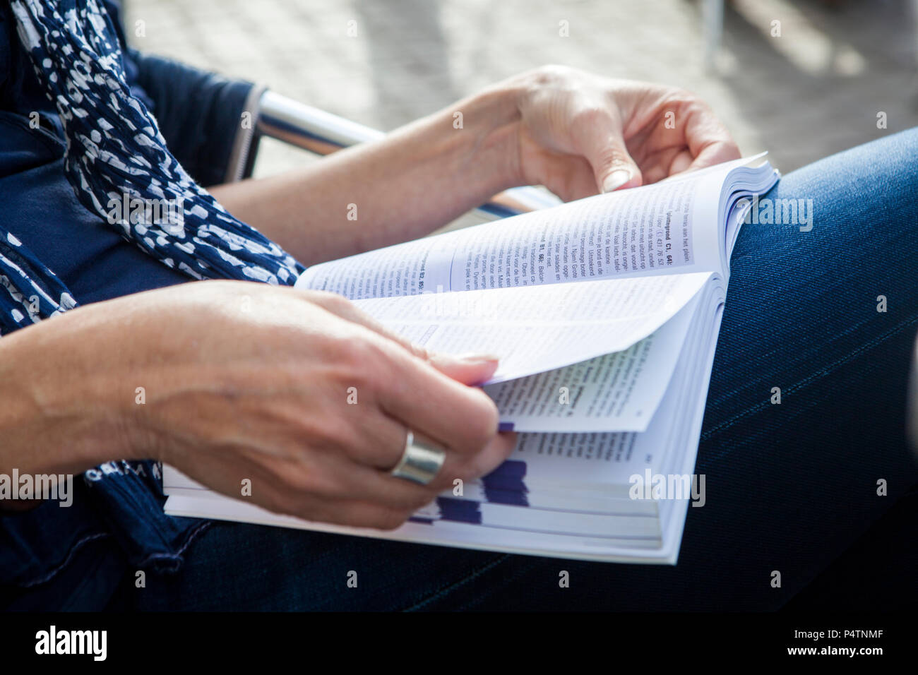 Woman reading a guidebook, seated in a chair Stock Photo - Alamy