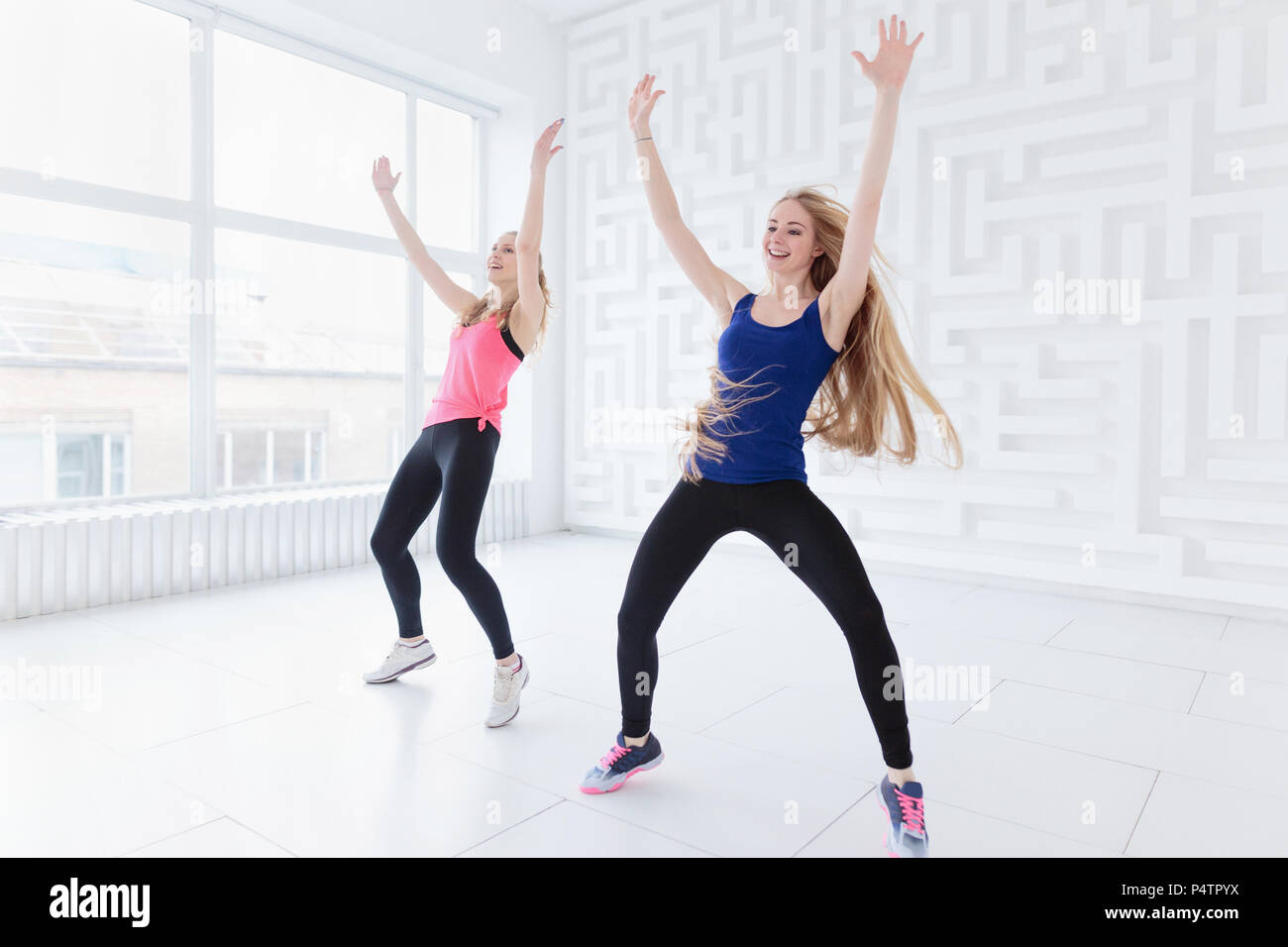 Happy young women performing a fitness dance with hands raised up Stock ...