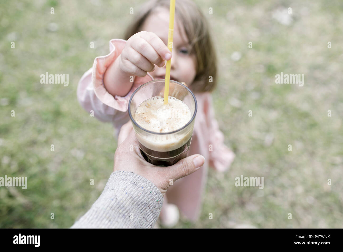 Little girl putting straw in glass of coffee Stock Photo - Alamy