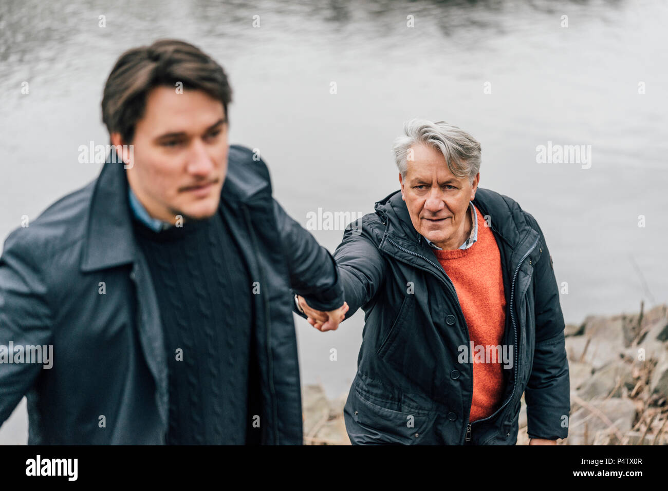 Young man supporting senior man at the riverside Stock Photo - Alamy