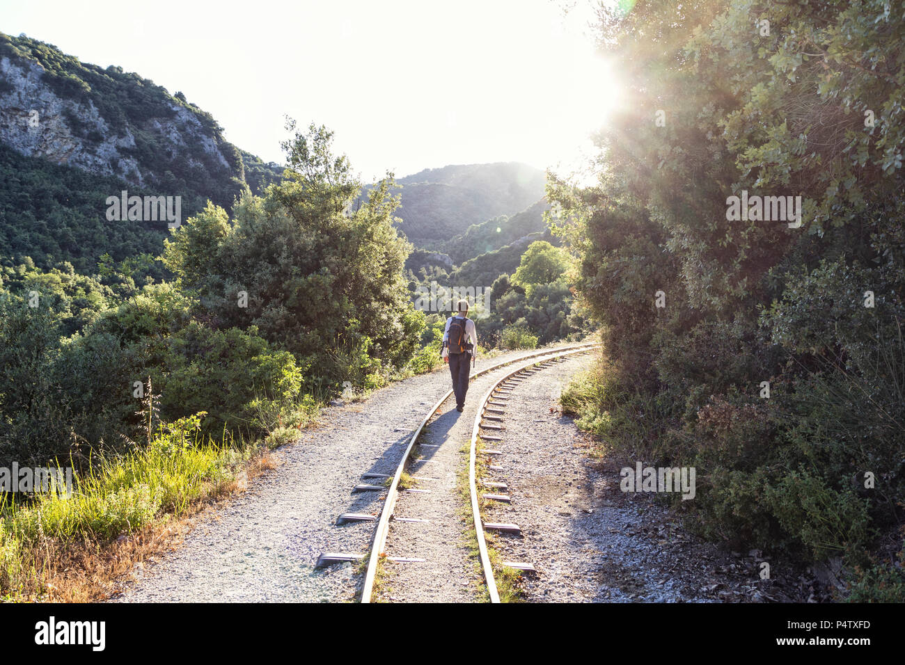 Greece, Pilion, Milies, back view of man walking along rails of Narrow ...