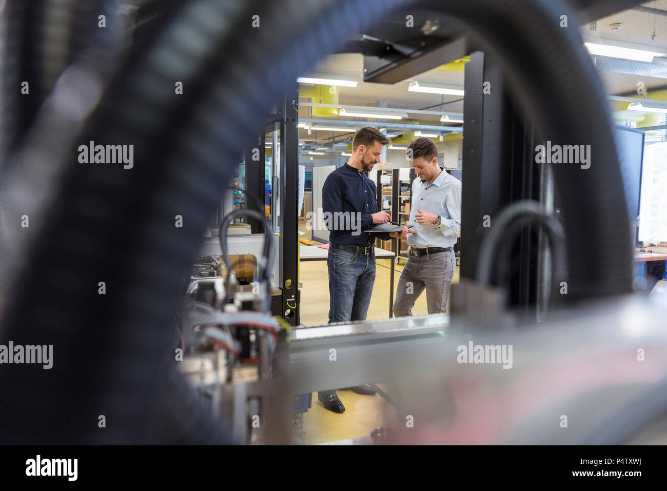Two men with tablet talking in factory Stock Photo - Alamy