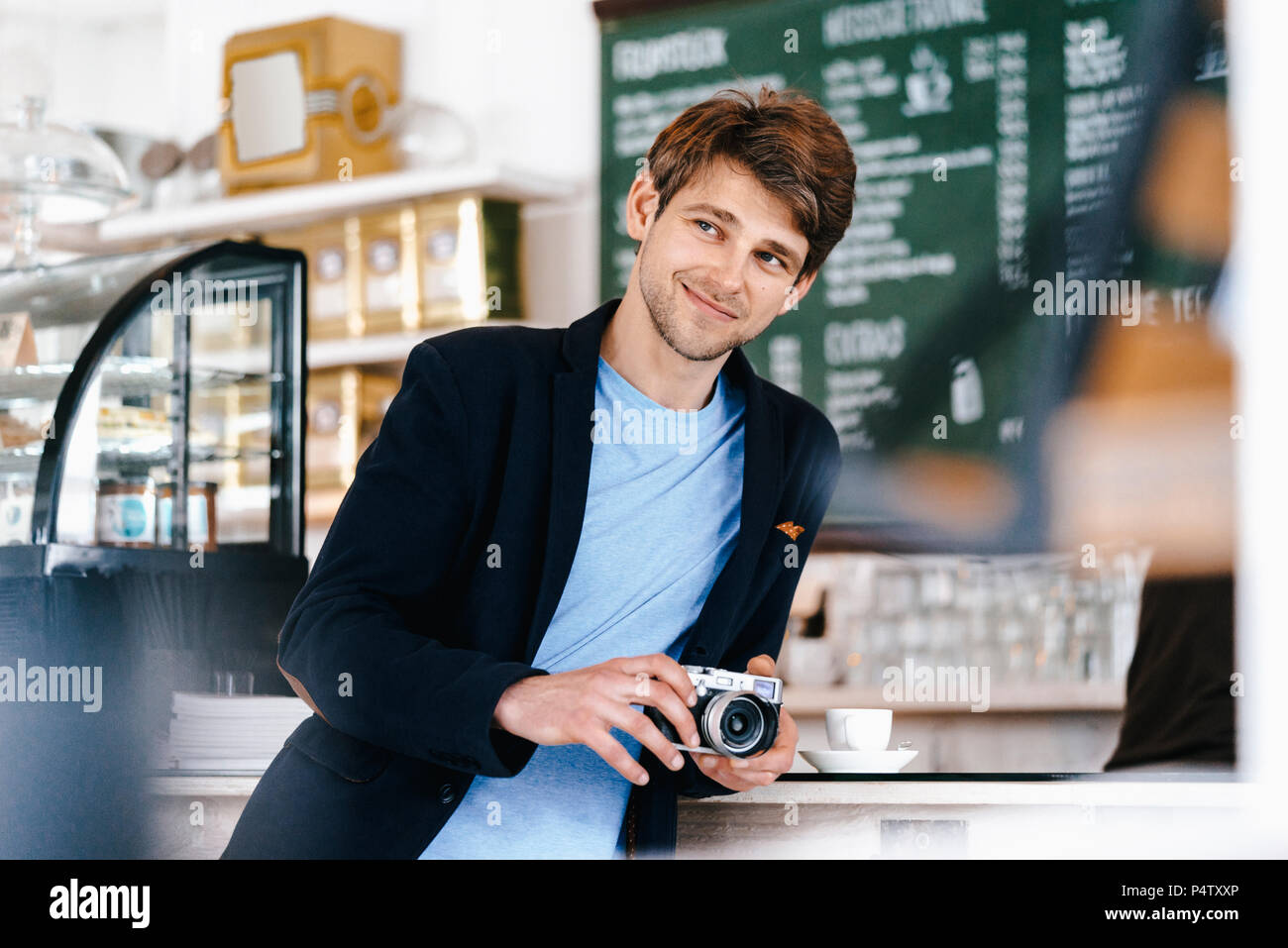 Smiling man in a cafe holding camera Stock Photo - Alamy