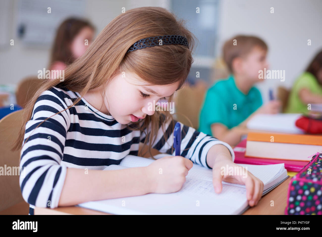 Schoolgirl writing in exercise book in class Stock Photo - Alamy