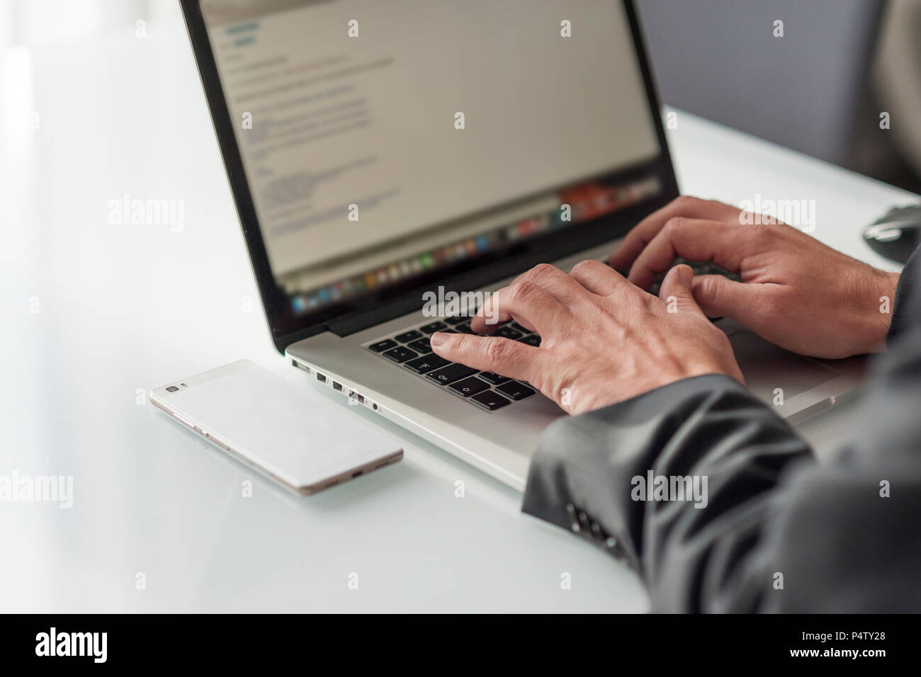 Man sitting at desk, using laptop Stock Photo - Alamy