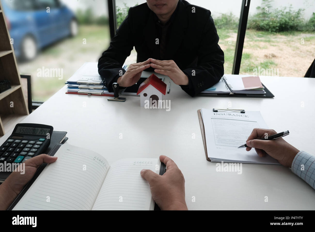 hand protecting house model. client signing home insurance contract ...