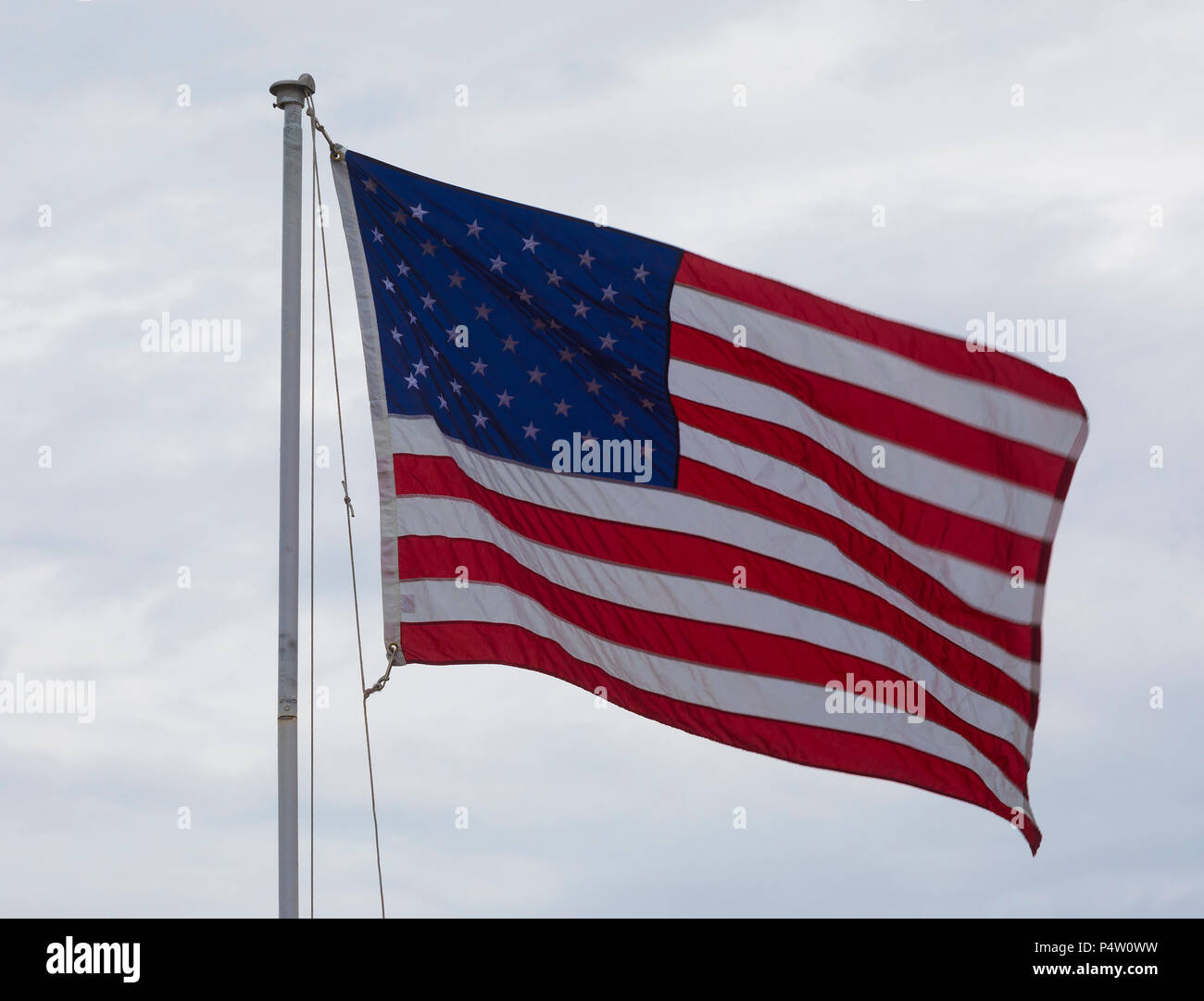 United States flag waving on a pole with clouds behind Stock Photo - Alamy
