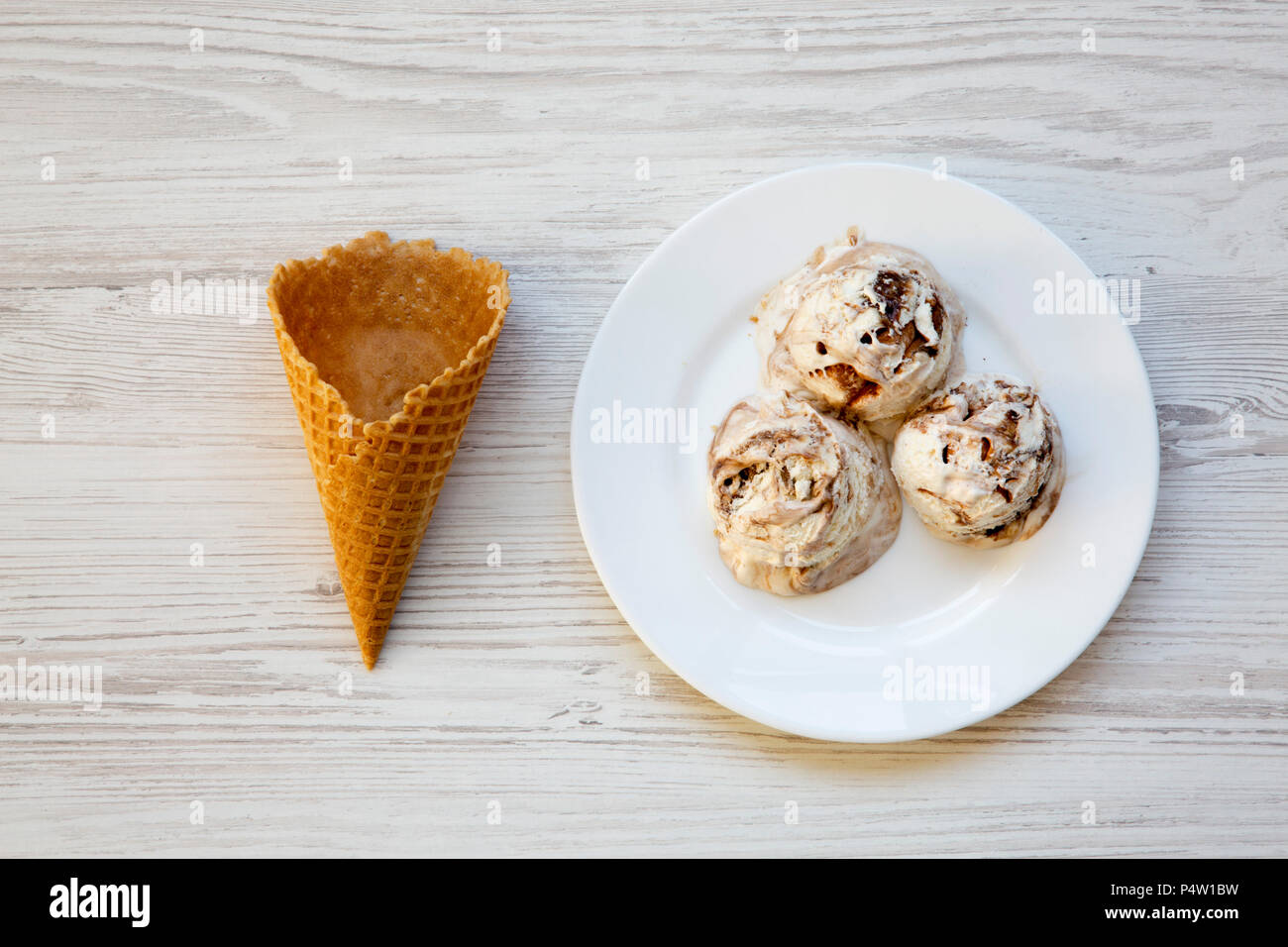 Top view, ice cream in white plate with sweet cone. Overhead, flat lay ...