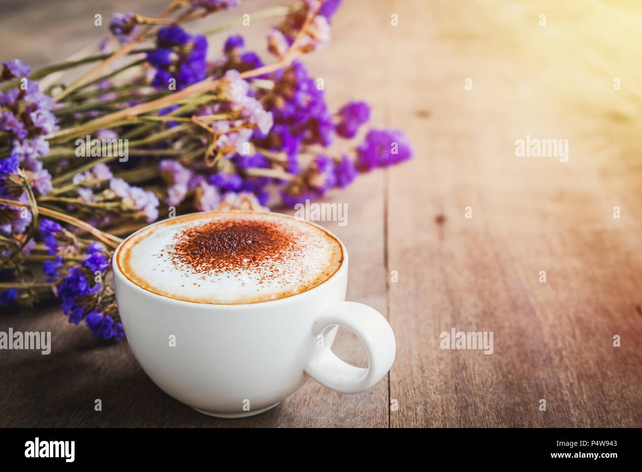 A cup of coffee with bouquet of violet dried flowers on wooden floor ...