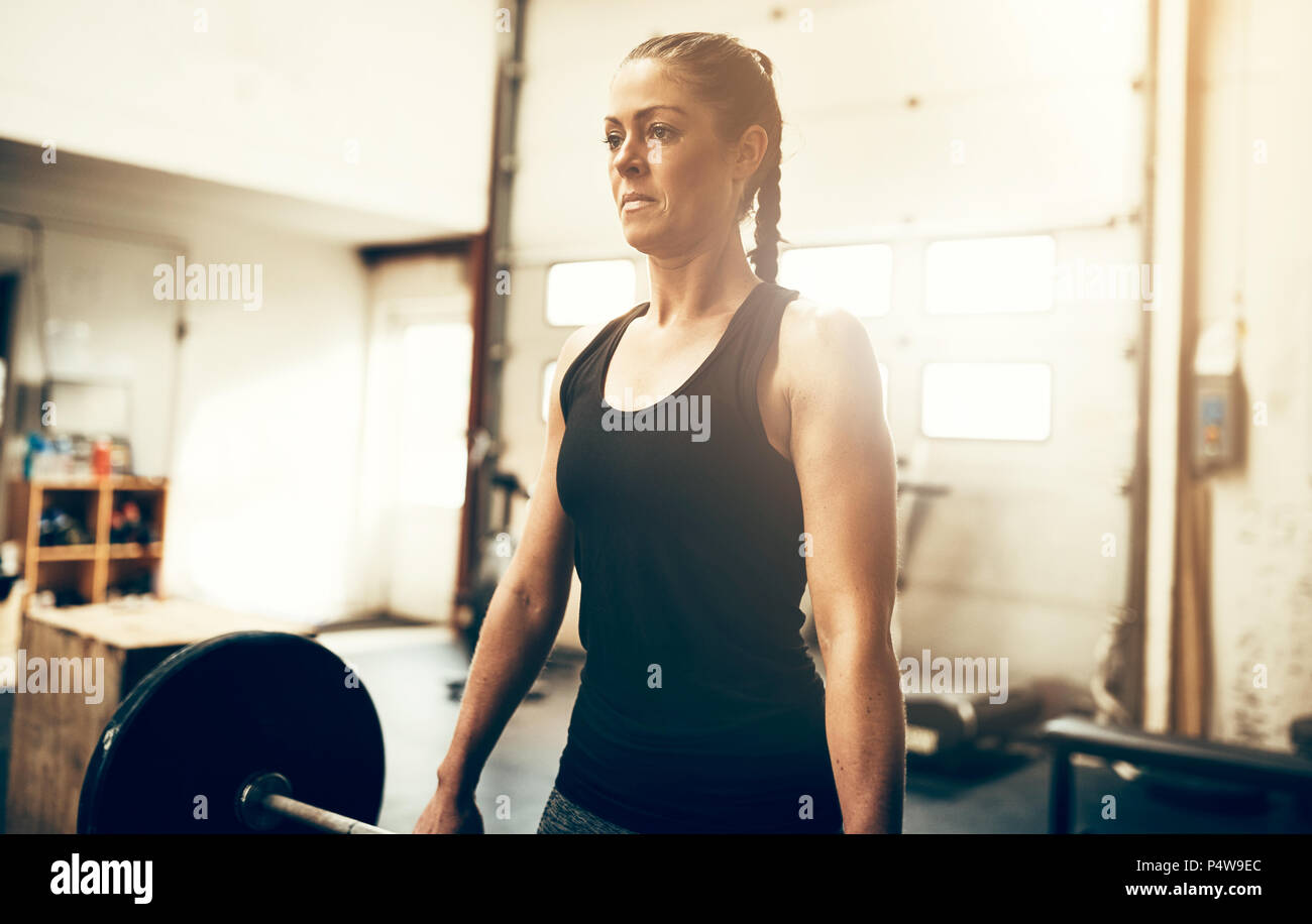 Fit young woman in sportswear lifting heavy weights while working out ...