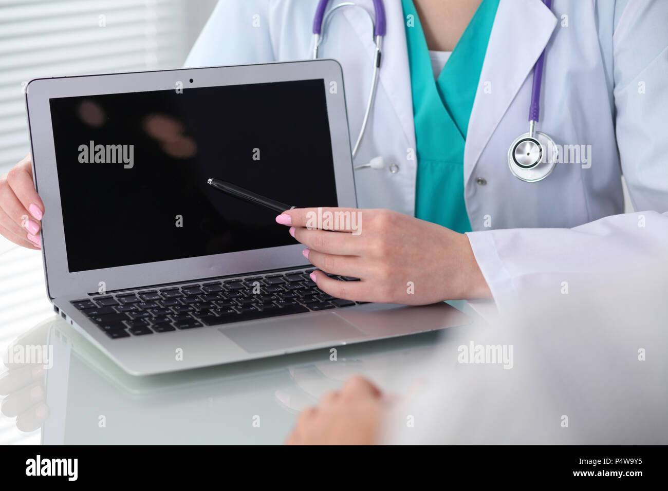 Doctor and patient, close-up. Physician pointing into laptop computer ...
