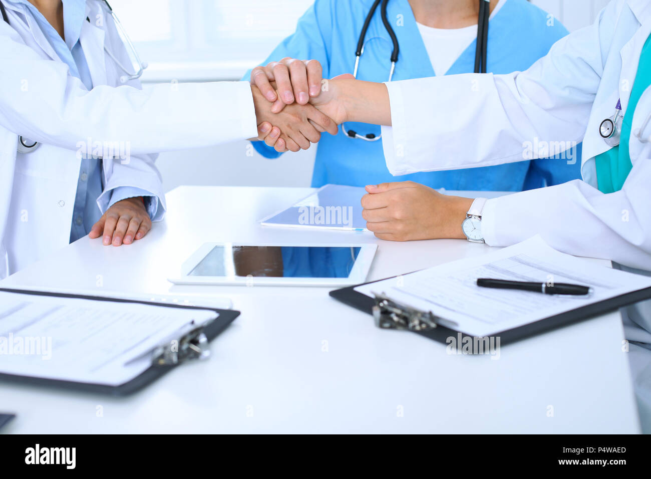 Two doctors shaking hands to each other at meeting. Teamwork and ...