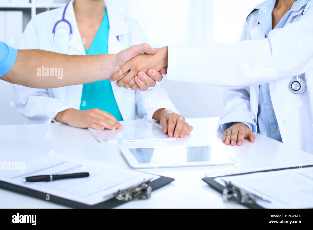 Two doctors shaking hands to each other at meeting. Teamwork and ...