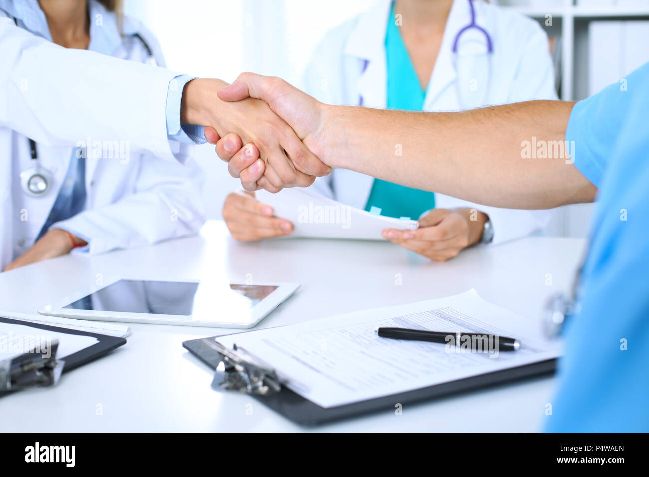 Two doctors shaking hands to each other at meeting. Teamwork and ...