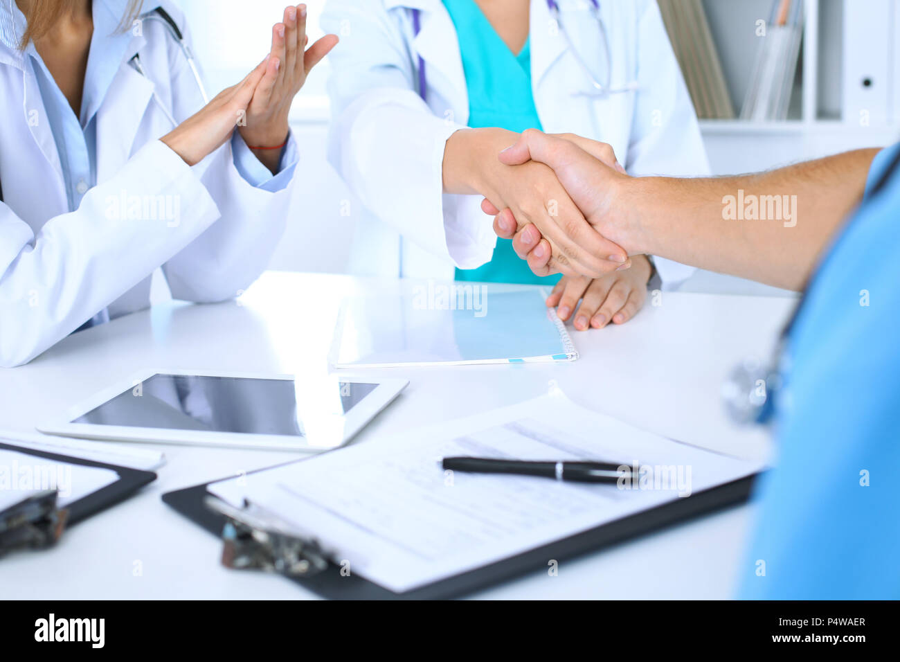 Two doctors shaking hands to each other at meeting. Teamwork and ...