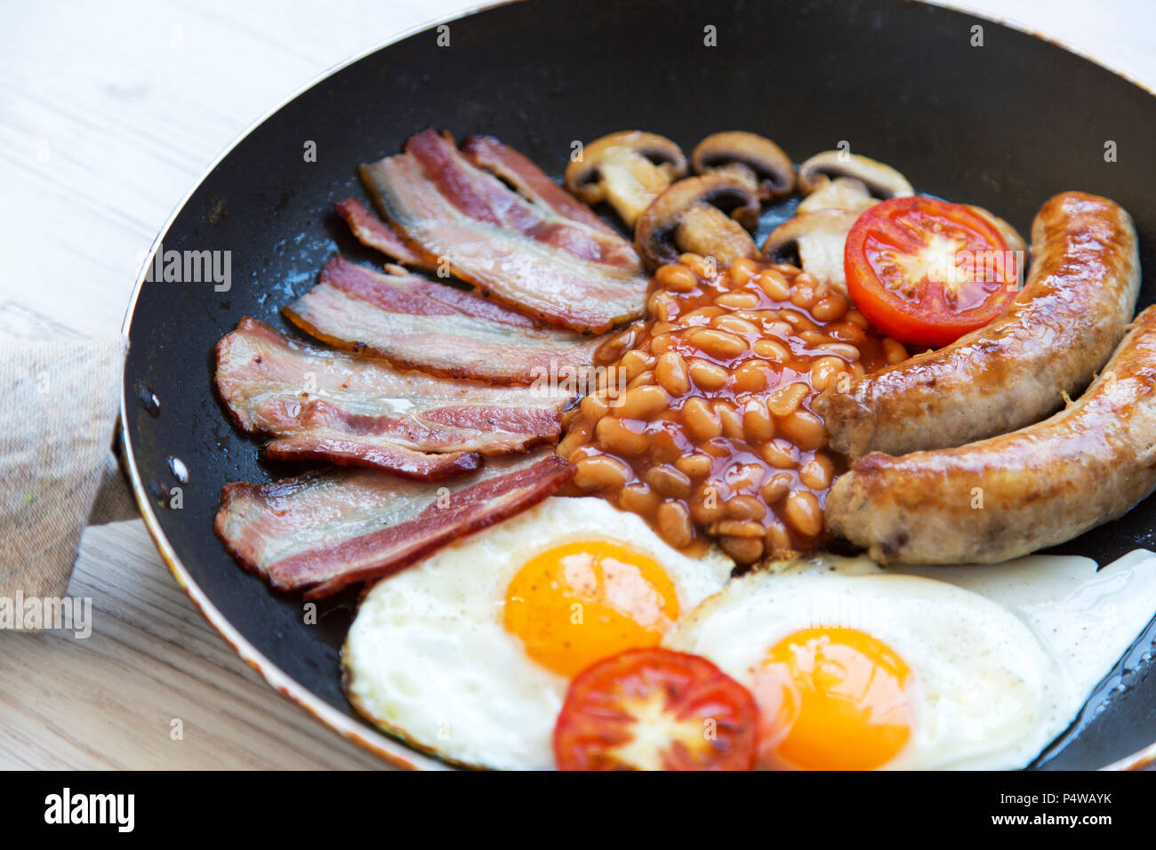 Full English breakfast in cooking pan with fried eggs, bacon, sausages ...