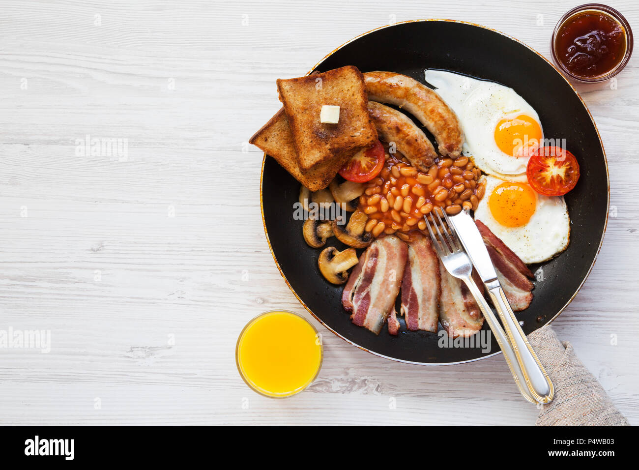 Full English breakfast in a pan with fried eggs, bacon, sausages, beans ...