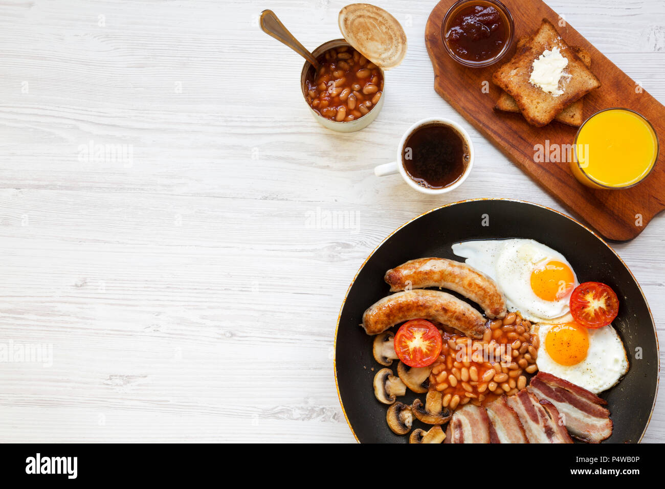 Full English breakfast in a pan with fried eggs, bacon, sausages, beans ...