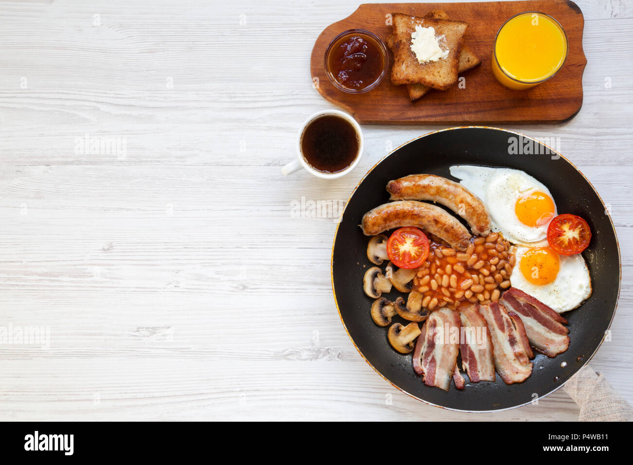 Full English breakfast in a pan with fried eggs, bacon, sausages, beans ...