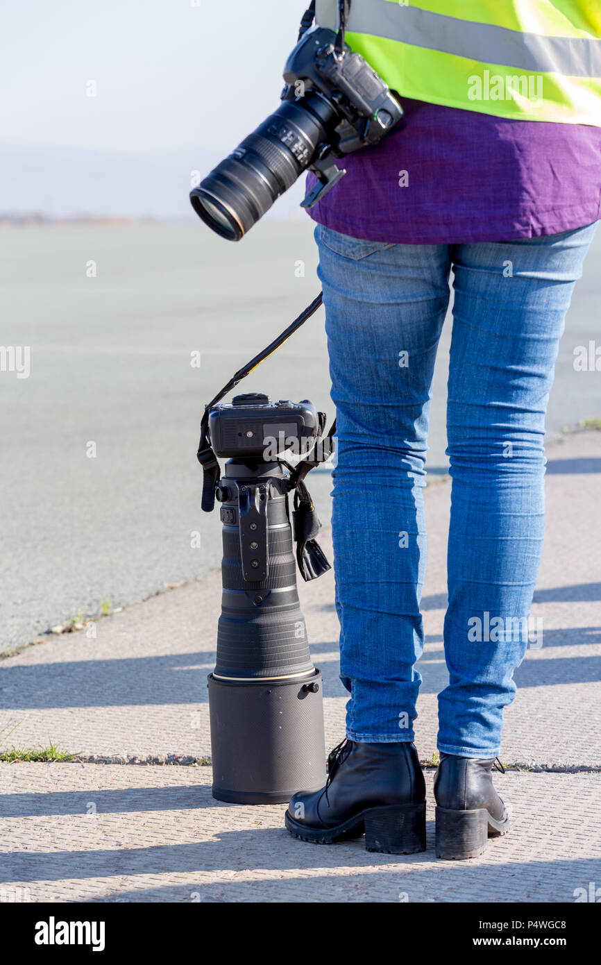 Photographer stands with modern digital camera and big telephoto lens ...
