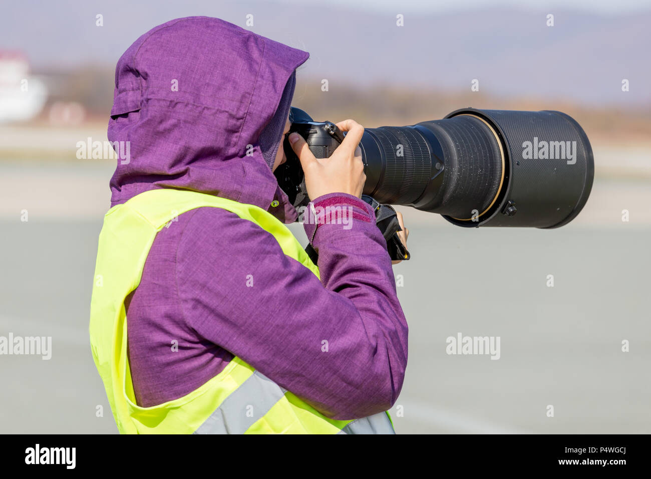 Photographer makes photo with modern digital camera and big telephoto ...