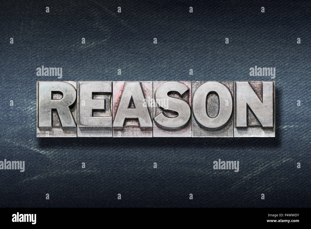 reason word made from metallic letterpress on dark jeans background ...