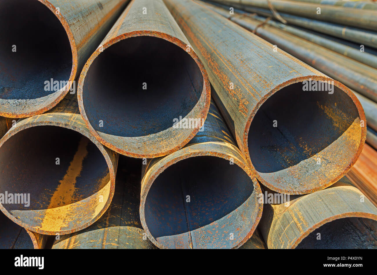 The manufactured by welding round rusty steel pipes piled up warehouse ...
