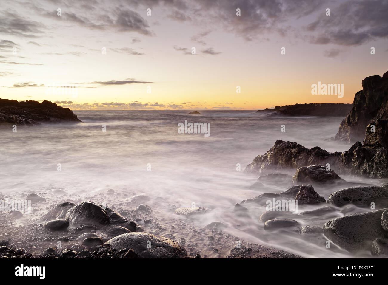 Volcanic beach with stones just after sunset, water movement in long ...