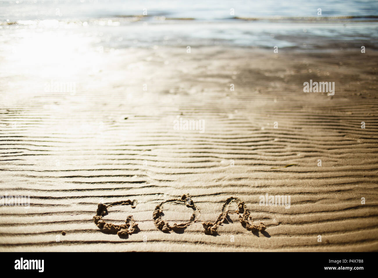 The word Goa is written on the sand by the sea. Trace on the beach ...