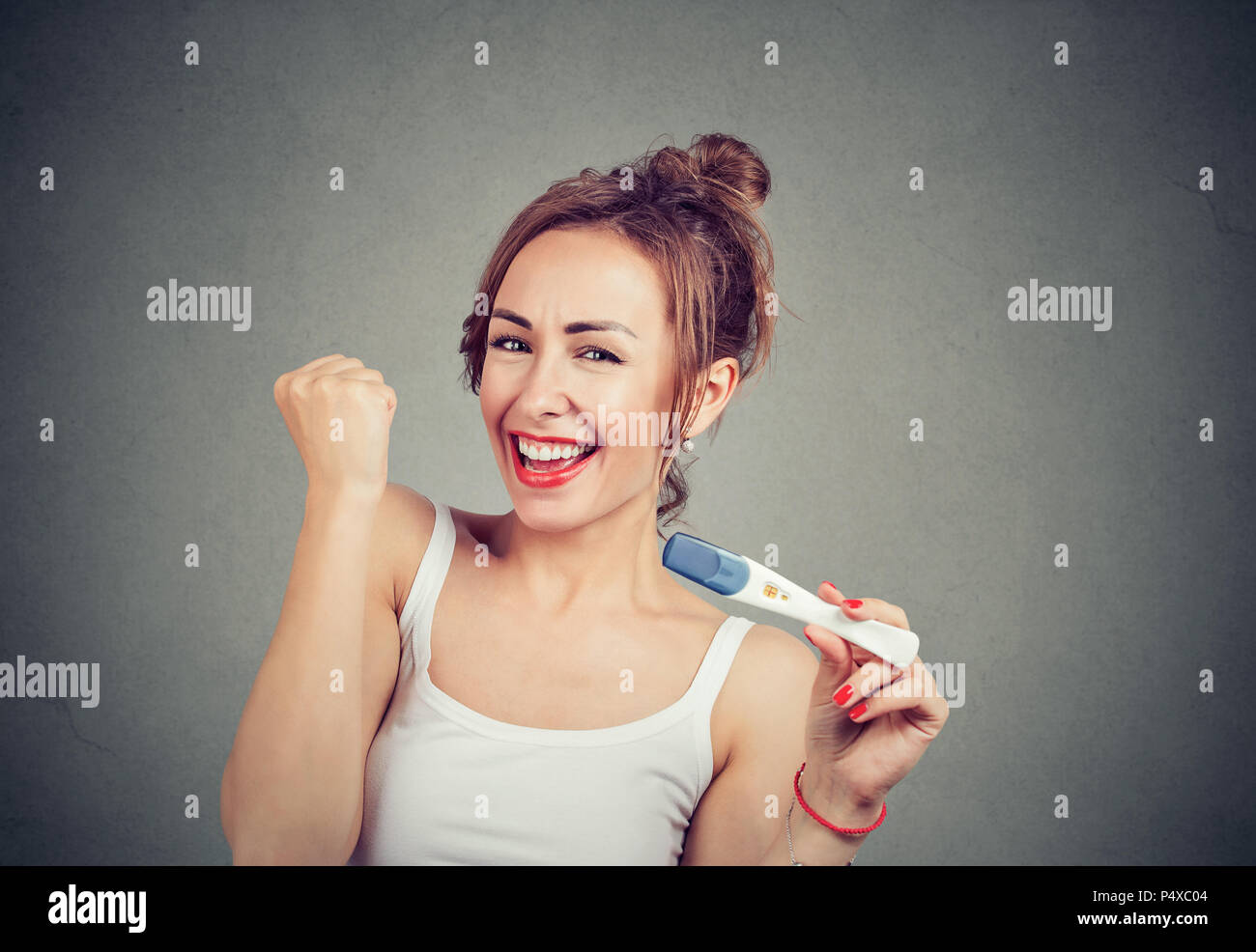 Happy young girl holding fits up and showing positive pregnancy test ...