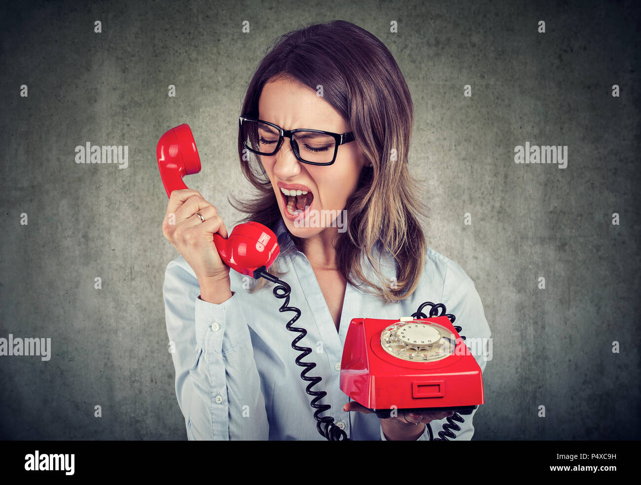 Portrait of a young angry business woman yelling at the red telephone ...