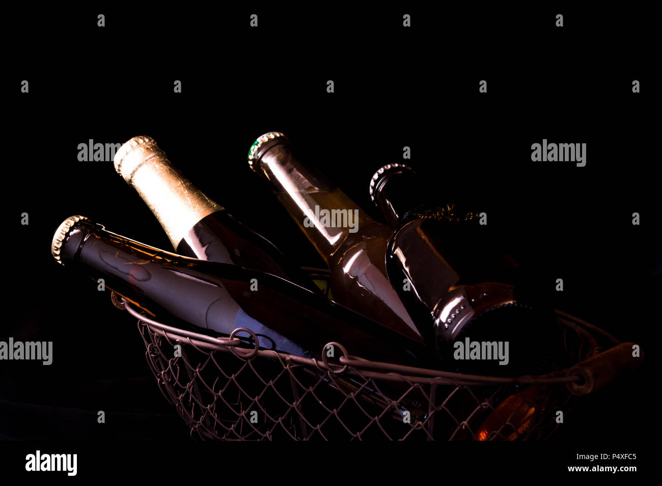 beer bottles on a black background chiaroscuro in an old metal mesh ...