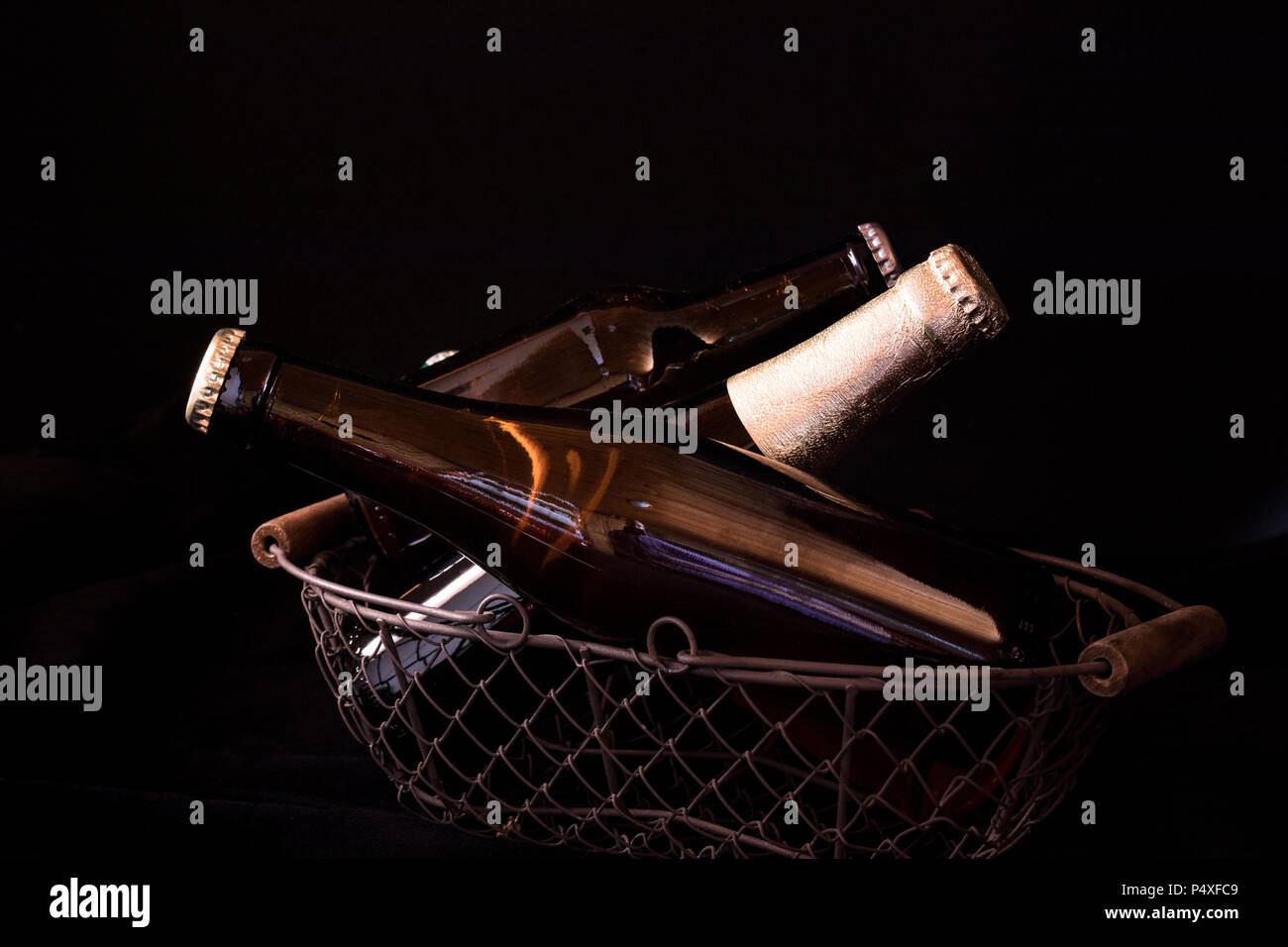 beer bottles on a black background chiaroscuro in an old metal mesh ...