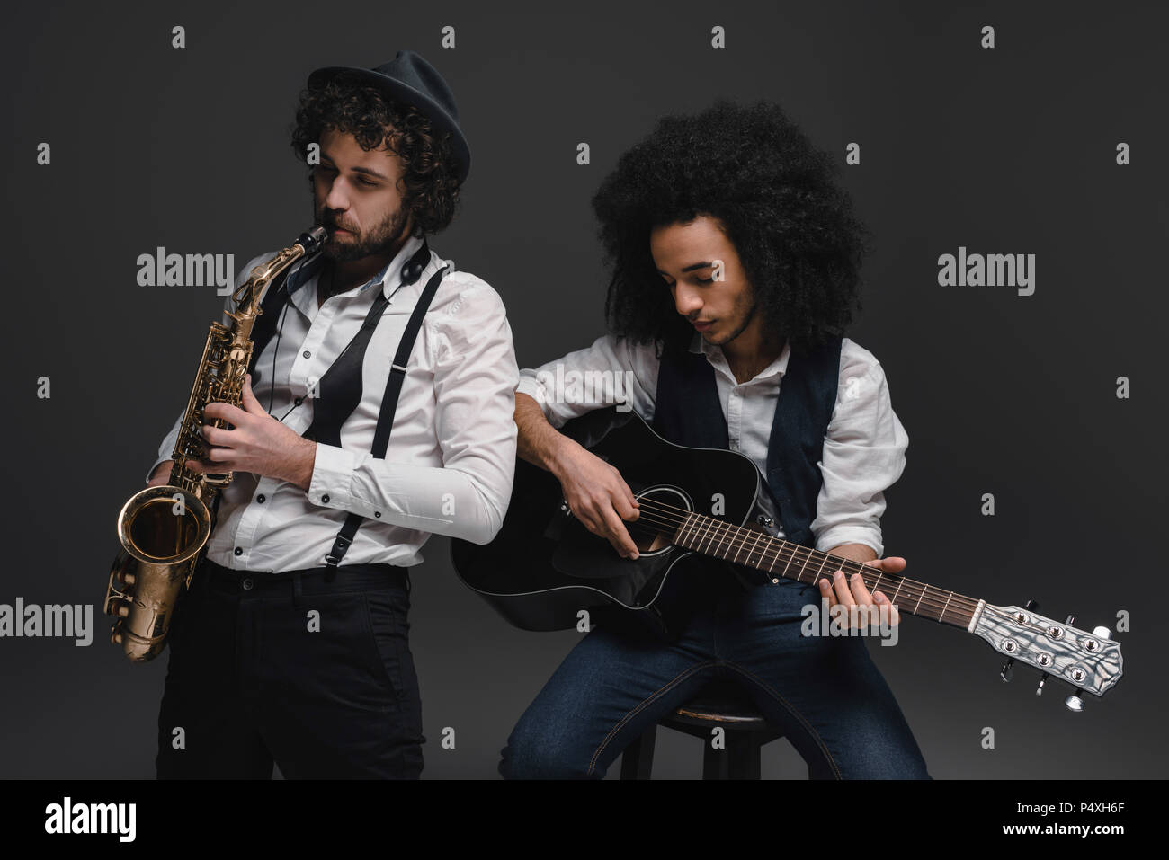 duet of musicians playing sax and acoustic guitar on black Stock Photo ...