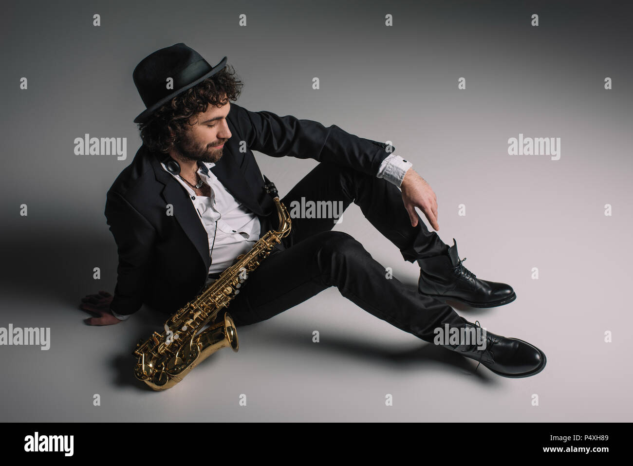 stylish musician sitting on floor with saxophone Stock Photo - Alamy