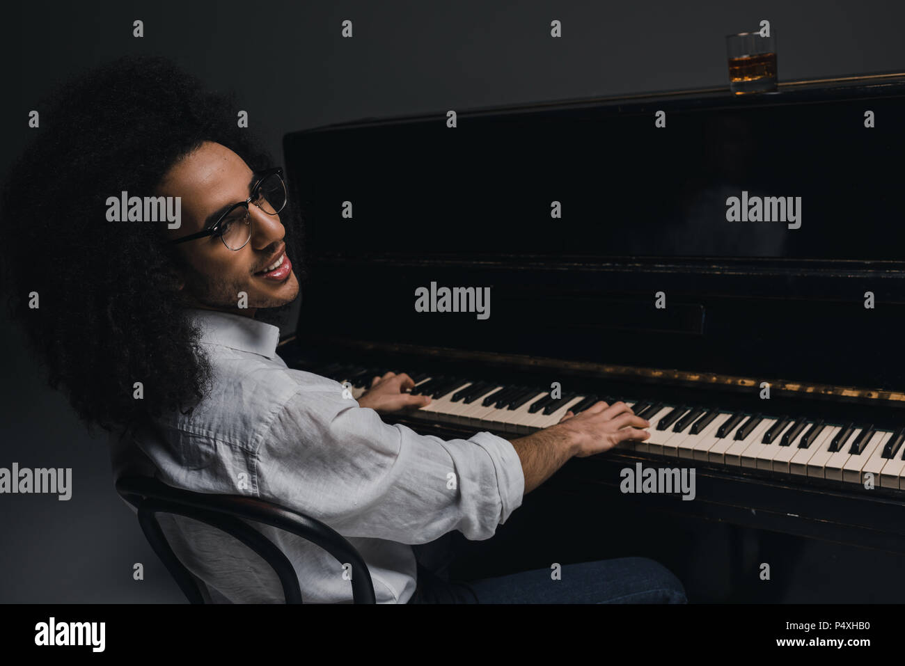 smiling young musician playing piano on black Stock Photo - Alamy