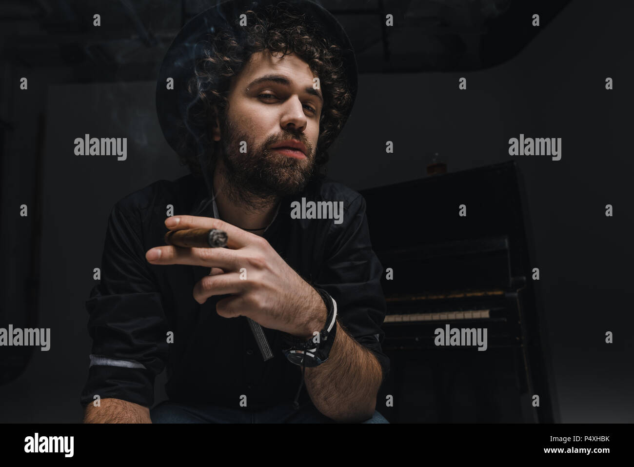 serious musician smoking cigar in front of piano on black Stock Photo ...