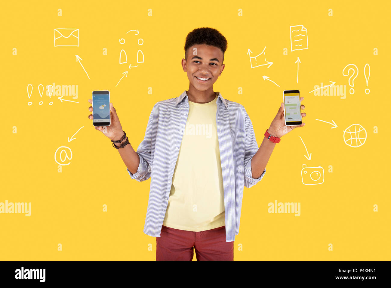 Positive young boy holding two smartphones and smiling happily Stock ...