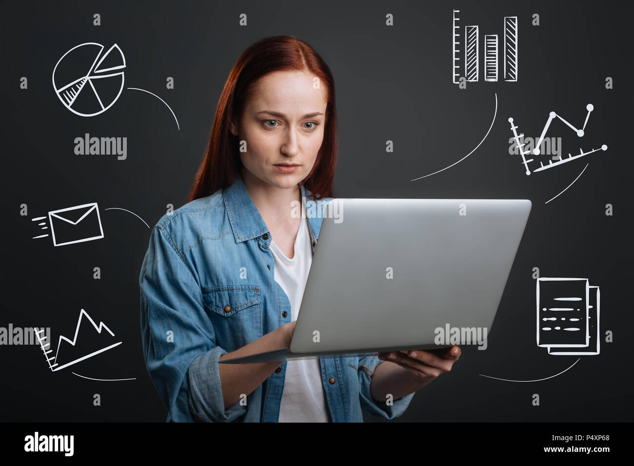 Confident programmer standing with a laptop and looking at the screen ...