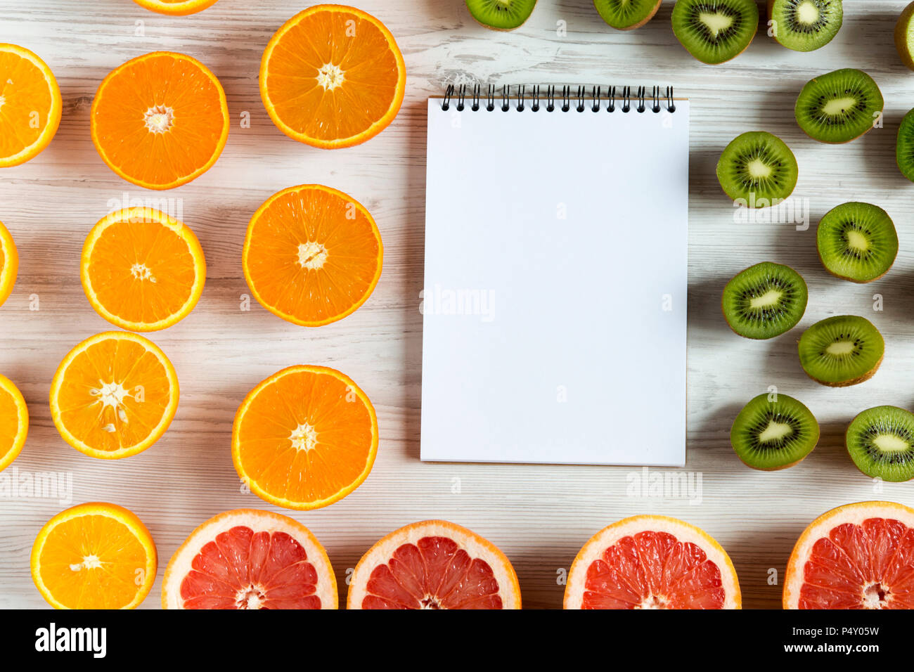 Flat lay Top view notebook with sliced kiwi, orange, grapefruit and ...